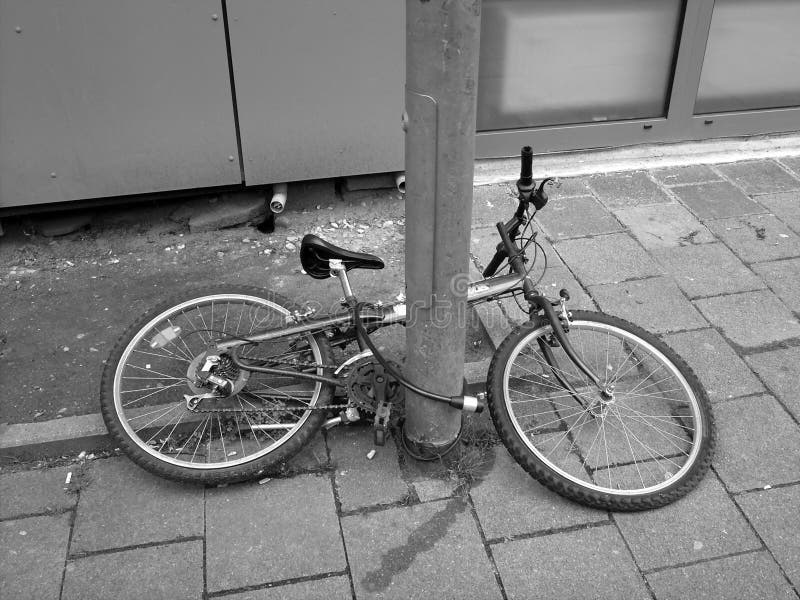 Grayscale Shot of a Bicycle Chained on the Metal Post in a Park Stock ...