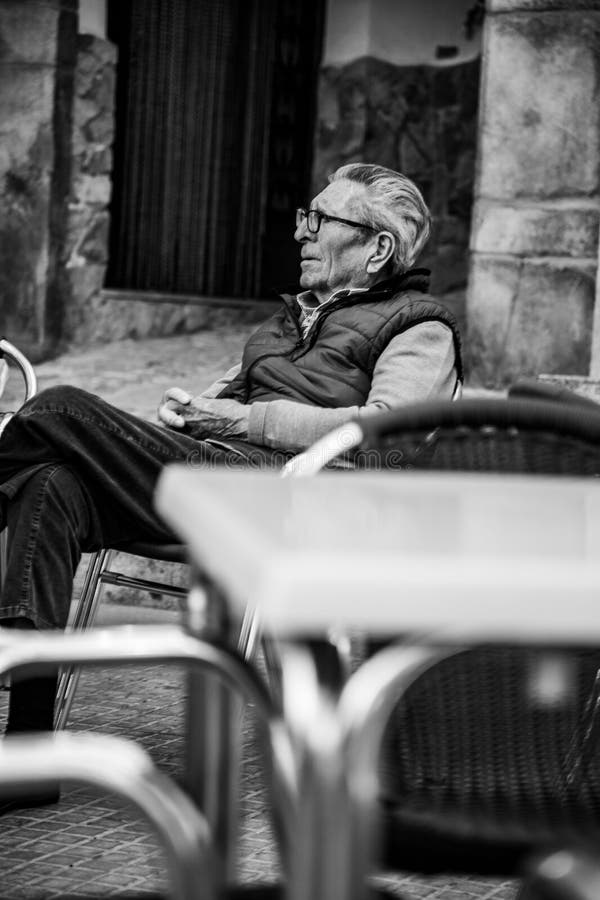 Grayscale Shot of an Elderly Person Resting on the Terrace of the Bar ...