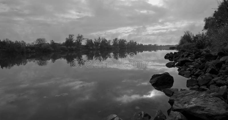 Grayscale Shot of a River, with Leafless Trees Under Cloudy Sky in the ...