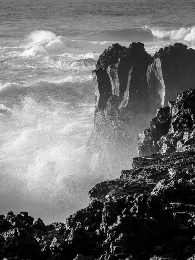 Grayscale Shot of Strong Waves Hitting Big Rocks on a Shore with Water ...