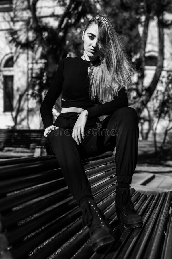 Grayscale Shot of a Young Pretty Female Posing Sitting on a Bench in ...