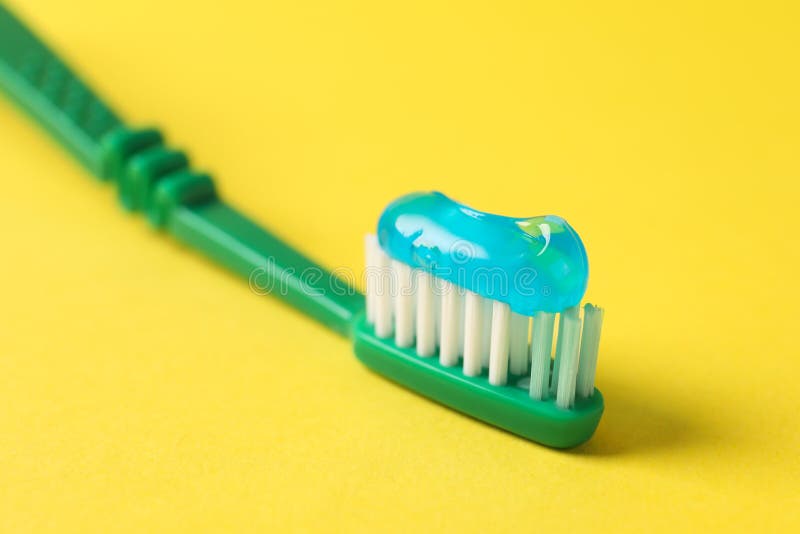 Green Brush with Toothpaste on Yellow Background, Closeup Stock Photo ...