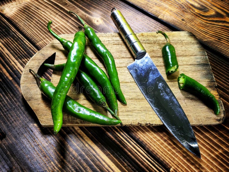 Green Chilies, Knife, and Sliced Chilies on a Wooden Cutting Board ...