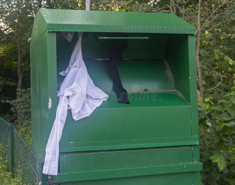 Green Container for Clothes, Clothes Sticking Out of the Container ...