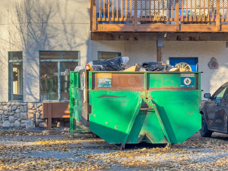 A Green Dumpster Overflowing with Garbage Parked in Front of a House ...