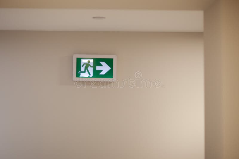 Green Emergency Exit Electric Light with White Arrow on White Wall ...