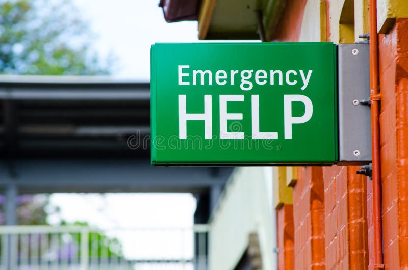 Green Emergency Help Sign Hanging from an Orange Wall. Stock Image ...