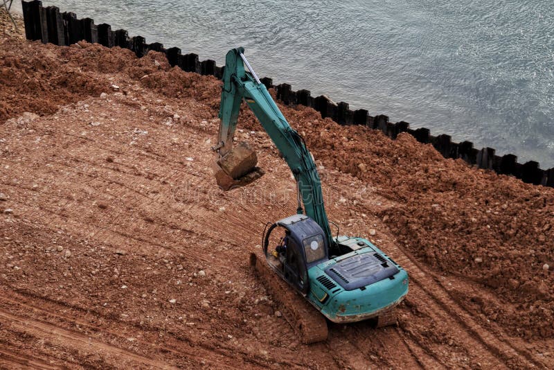 Green Excavator Flatten the Ground Near the Water or the River Stock ...