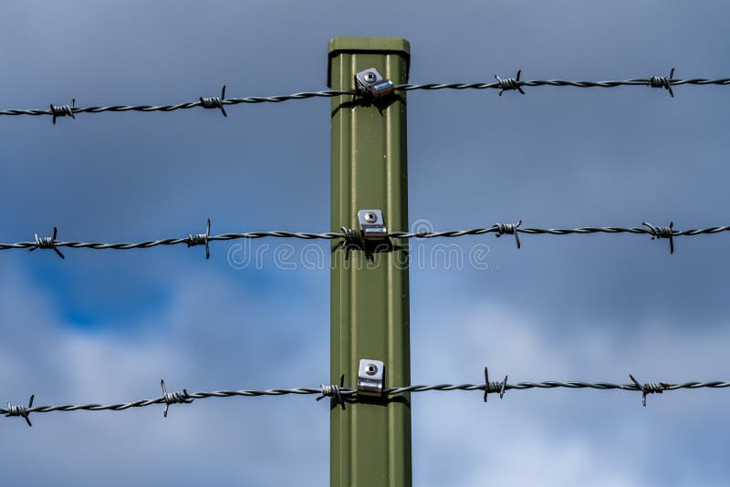 Green Fence Pole with Three Rows of Barbwire Stock Image - Image of ...