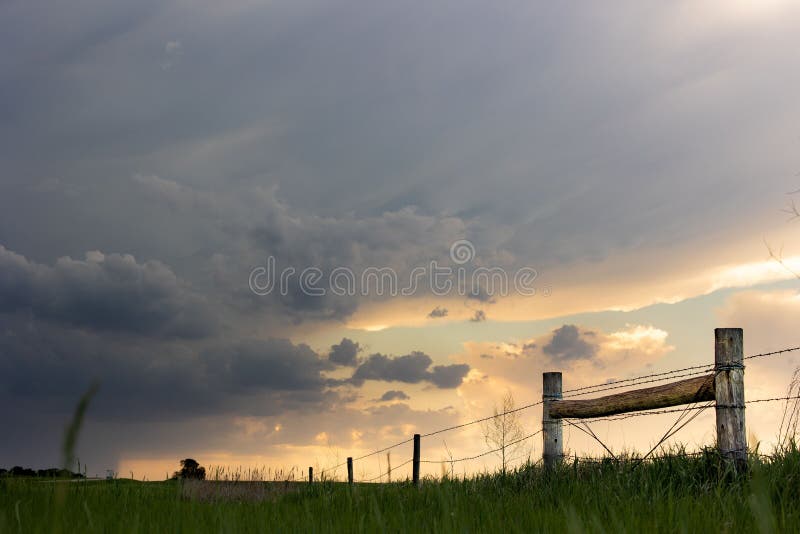 Green Field Fenced Off with a Blue Cloudy Sky in the Background Stock ...