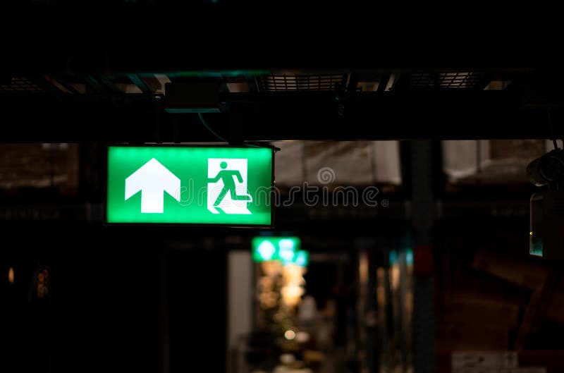 Green Fire Escape Sign Hang on the Ceiling in the Warehouse. the ...