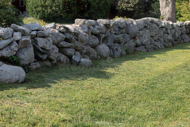 Green Grass and Mature Bushes Separated by a Stacked Stone Wall Stock ...