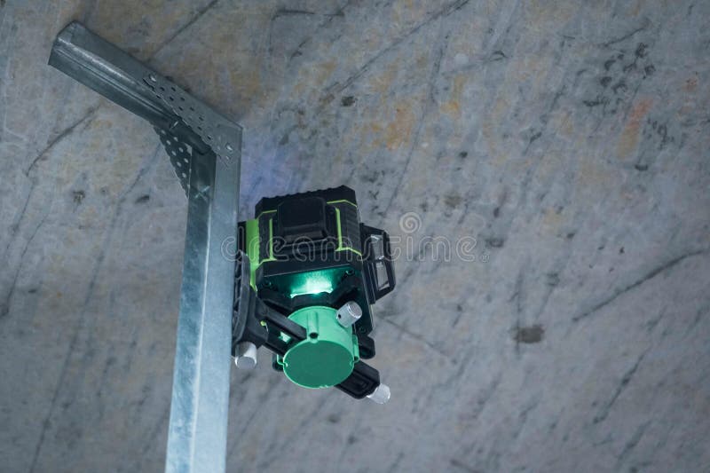 A Green Laser Level Rests on a Bare Ceiling, Highlighting Its Role As a ...