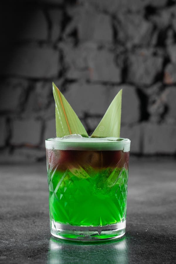Green Layered Cocktail Decorated with Bamboo Leaves on a Gray ...