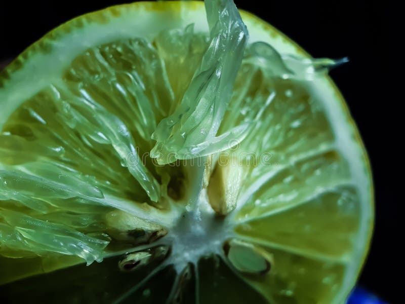 A Green Lemon is Cut in the Middle and the Seed and Lemon Juice in the ...