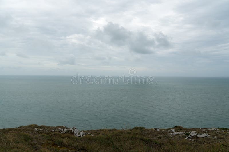 Green Meadow and Cliff with Ocean View Under Overcast Sky Stock Photo ...
