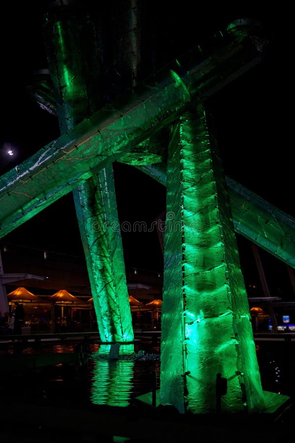 Green Olympic Torch Pillars Statue Reflected in Water at Night ...