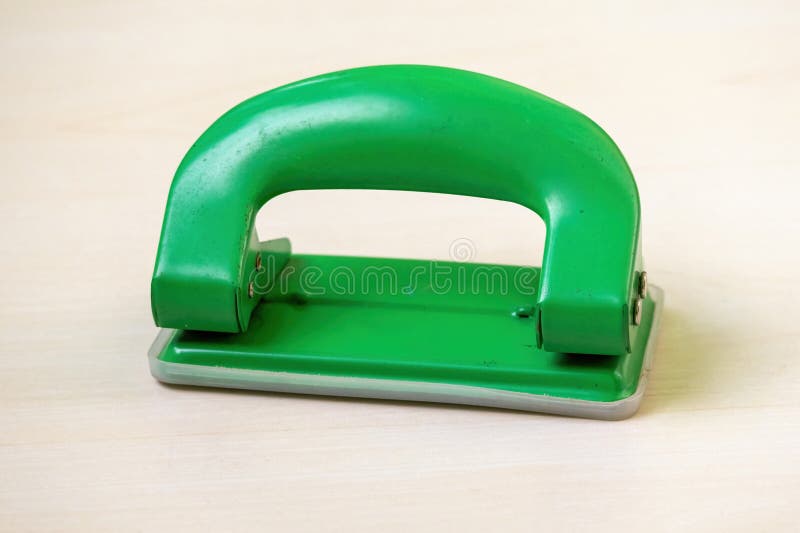 A Green Paper Hole Puncher or Punch Machine on a Light Wooden Surface ...