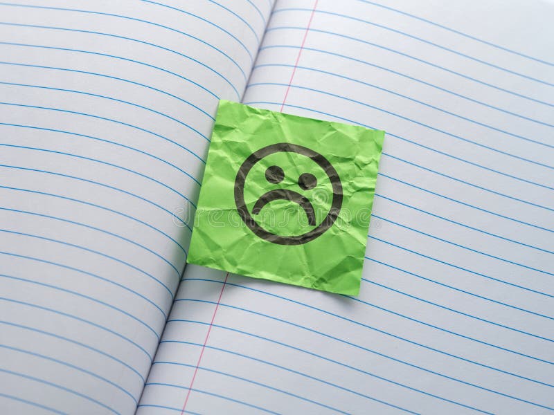 A Green Paper Note with a Sad Face on it Lying in an Open Notebook ...