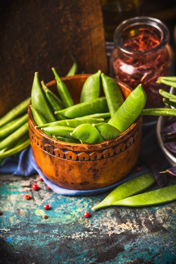 Green Pea Pods with Cooking Ingredients in Bows on Rustic Kitchen Table ...