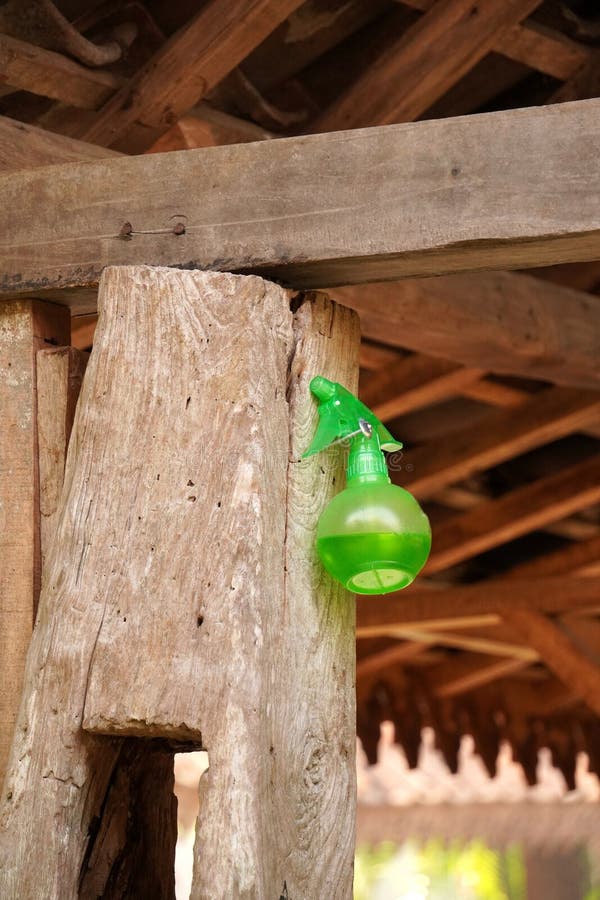 A Green Plastic Spray Bottle Hangs from a Nail Embedded in a Large ...