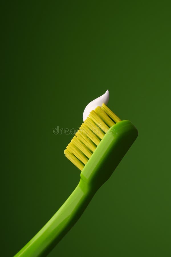 Green Plastic Toothbrush with White Toothpaste on a Green Background ...