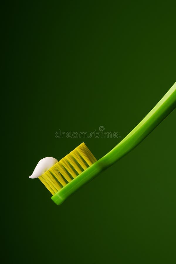 Green Plastic Toothbrush with White Toothpaste on a Green Background ...