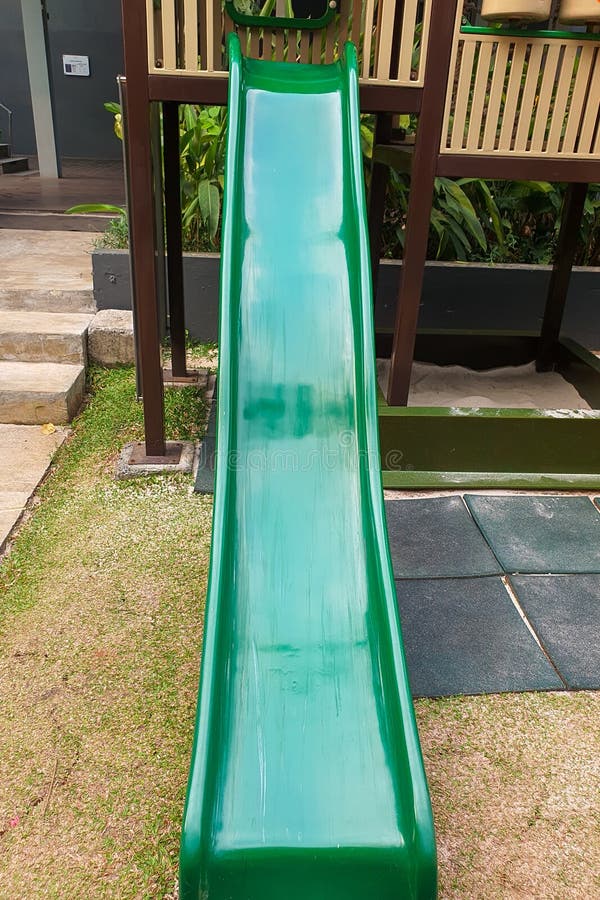 A Green Slide Leading Down from a Wooden Children Playground Structure ...