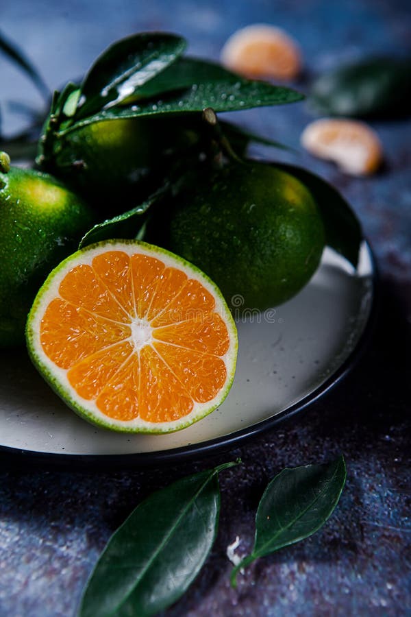 Green Tangerines on a Dark Marble Tabletop, Close-up, Unripe Tangerines ...