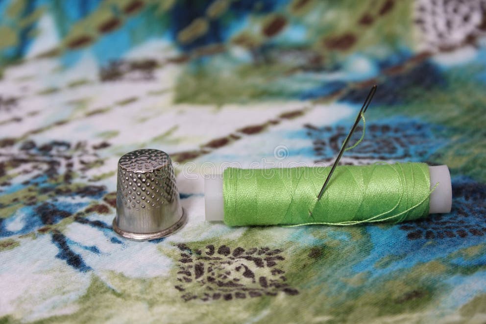 Green Thread with Thimble and Scissors on Vintage Fabric Stock Photo ...
