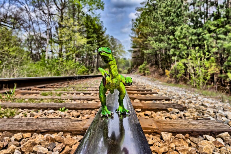 Green Velociraptor Dinosaur Walking on Rail Railroad Tracks Stock Photo ...