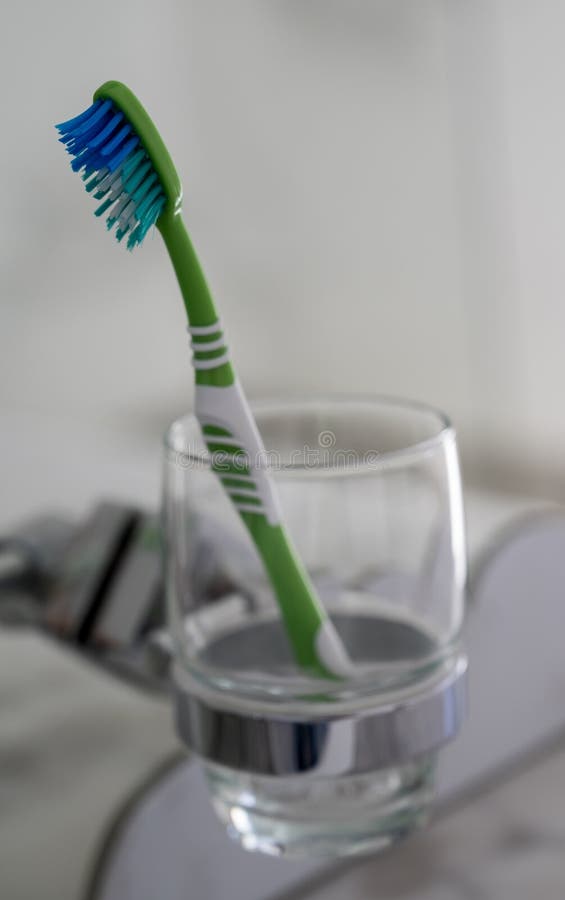 Green and White Toothbrush is Kept in a Transparent Glass Cup. Stock ...
