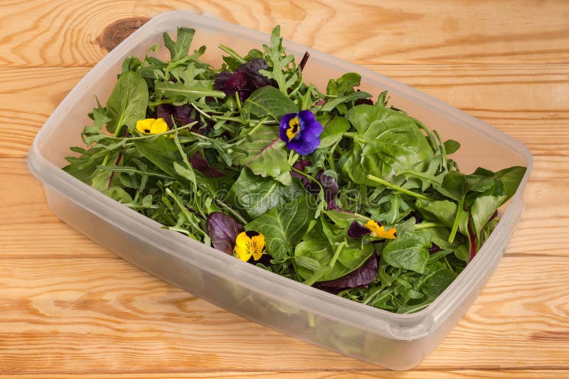 Greens with Edible Flowers in Plastic Container on Rustic Table Stock ...