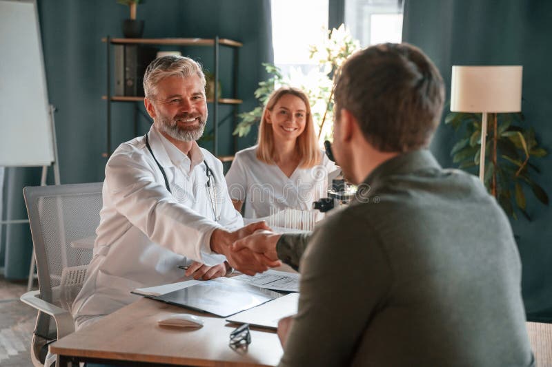 Greetings, Making Handshake. Two Doctors Consult a Patient in a Clinic ...