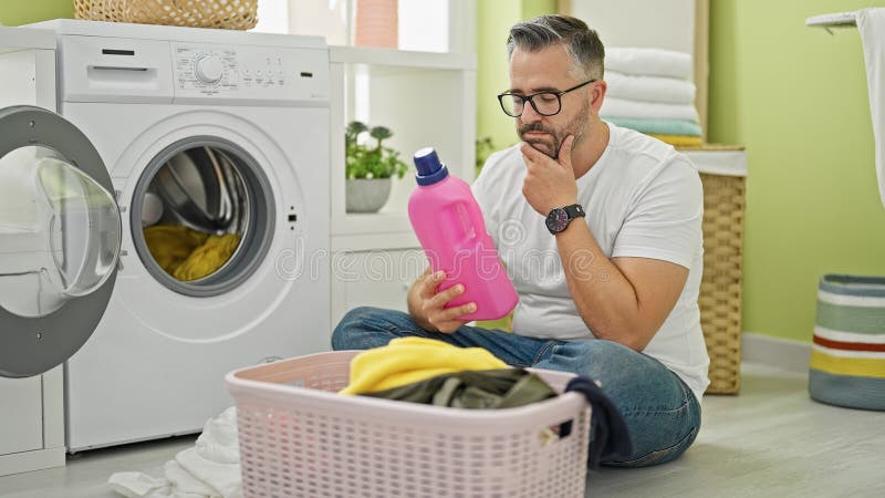 Grey-haired Man Washing Clothes Holding Detergent Bottle Thinking at ...