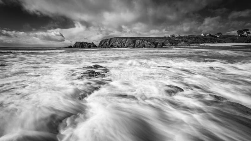 Greyscale Shot of Rock Formations in the Foamy Water of the Sea at ...