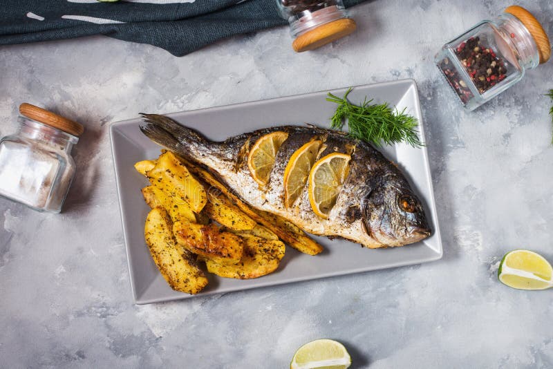 Grilled Fish on Stone Plate with Lemon on Concrete Background Stock ...