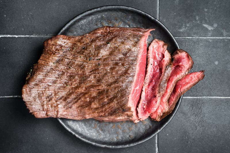 Grilled Flap or Flank Steak, Sliced on a Plate. Black Background Stock ...
