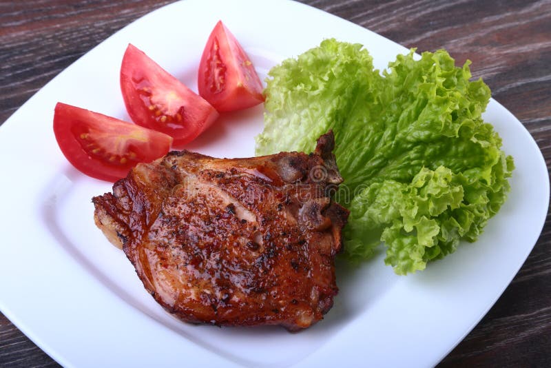Grilled pork chops with tomato, leaves lettuce and ketchup on plate ...