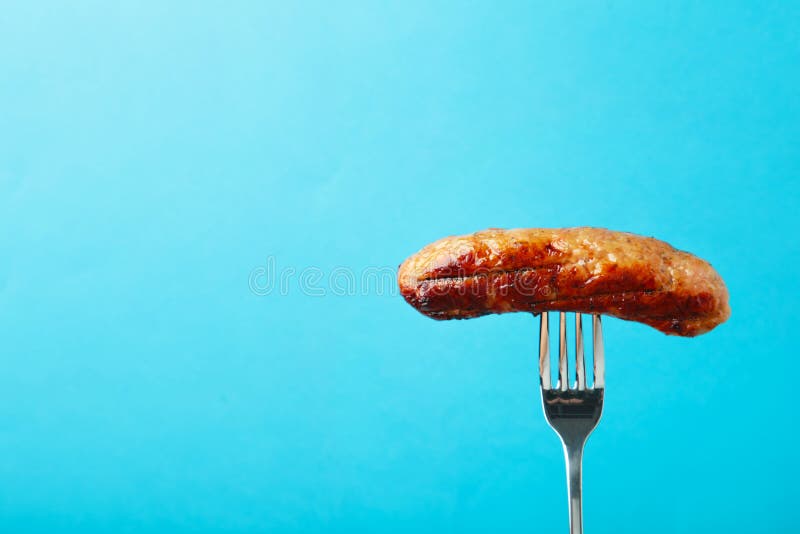 Grilled Sausage on a Fork on Blue Background with Copy Space Stock ...