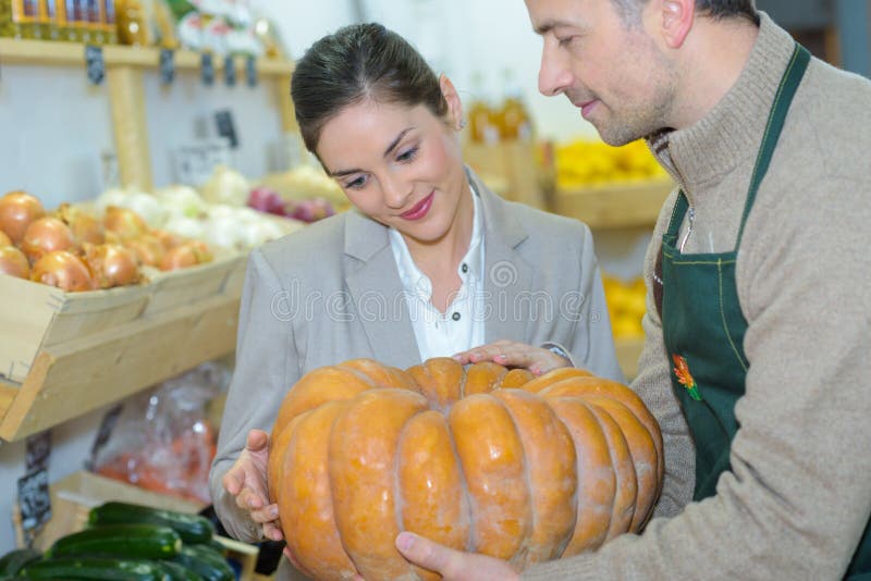 Grocer Showing Pumpkin To Customer Stock Photo - Image of hold, smile ...