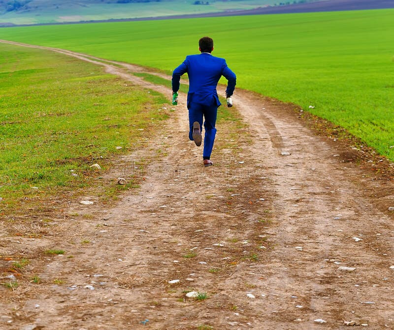 Groom in Blue Suit Running Away with Beer Bottles on a Field Path ...
