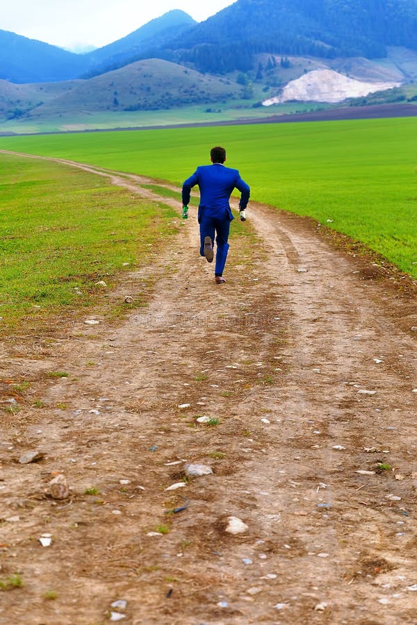 Groom in Blue Suit Running Away with Beer Bottles on a Field Path ...