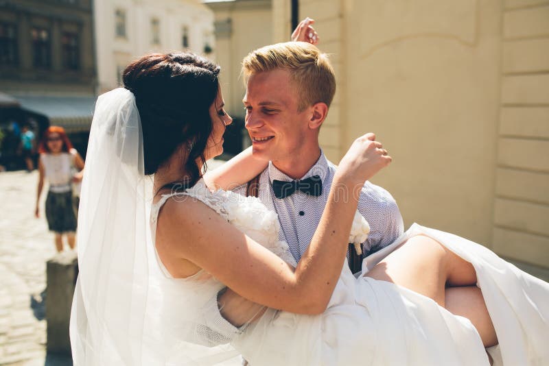 Groom Carries Bride in His Arms Stock Photo - Image of happy, male ...