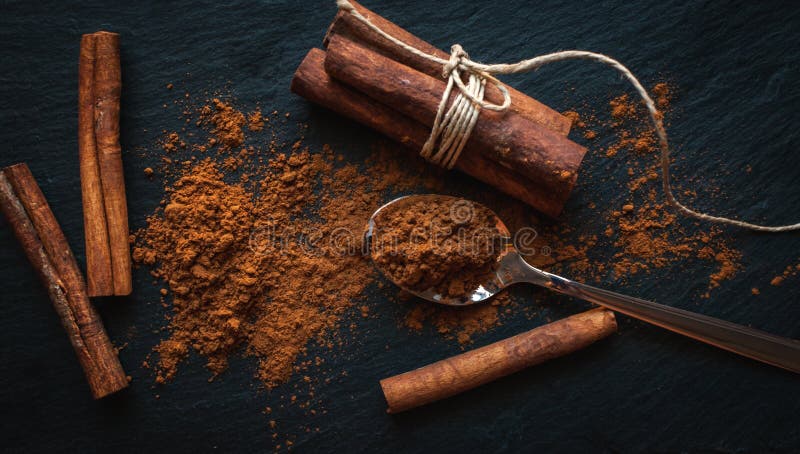Ground Cinnamon in Teaspoon, and Cinnamon Sticks on Dark Background ...