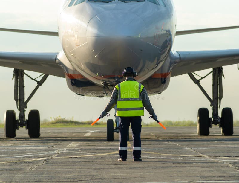 Ground Crew Signaling To Airplane on Wet Runway Stock Image - Image of ...