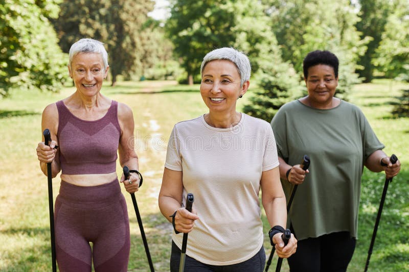 Group of Active Senior Women Walking with Poles Outdoors and Smiling ...