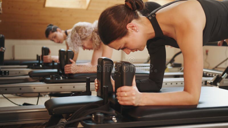 Group of Active Woman Making Plank Exercise while Workout on Reformer ...