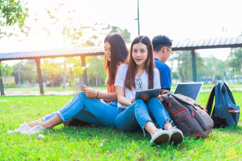 Group of Asian College Student Using Tablet and Laptop on Grass Field ...