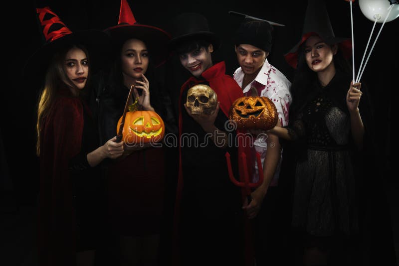 Asian Friends In Spooky Costume Of Witch And Vampire With Pumpkin Head